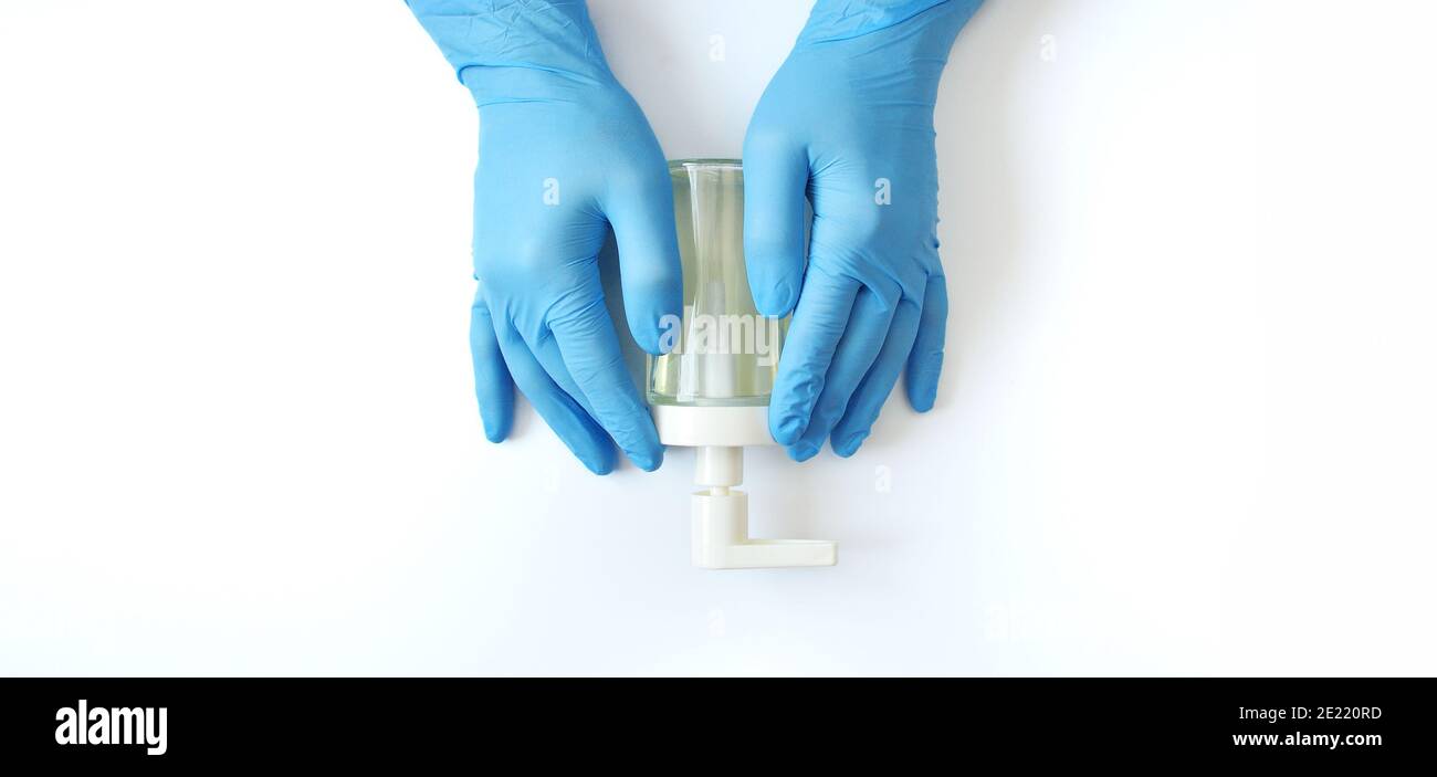 Hand sanitizer bottle and blue gloved hands close up. Call for hand ...