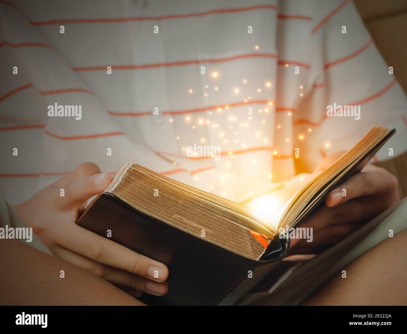 Hand of child opening the gold edge magic book with mystic bright spark ...