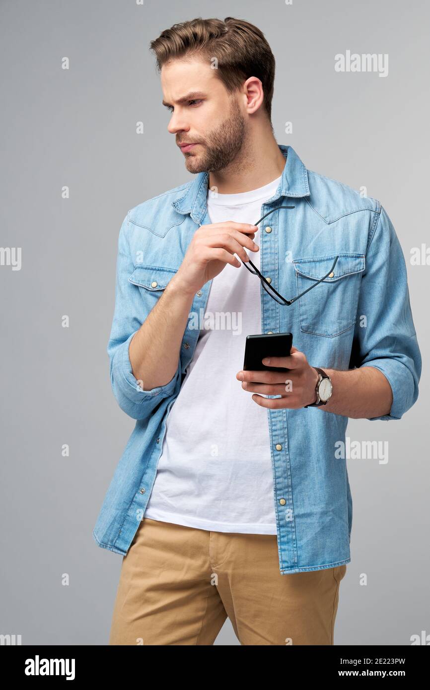 pretty casual man in blue jeans shirt holding his phone standing over ...
