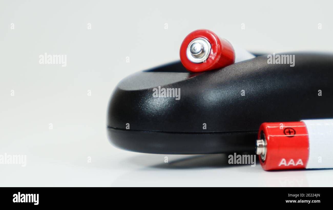 Black TV remote control with AAA alkaline batteries on a white ...