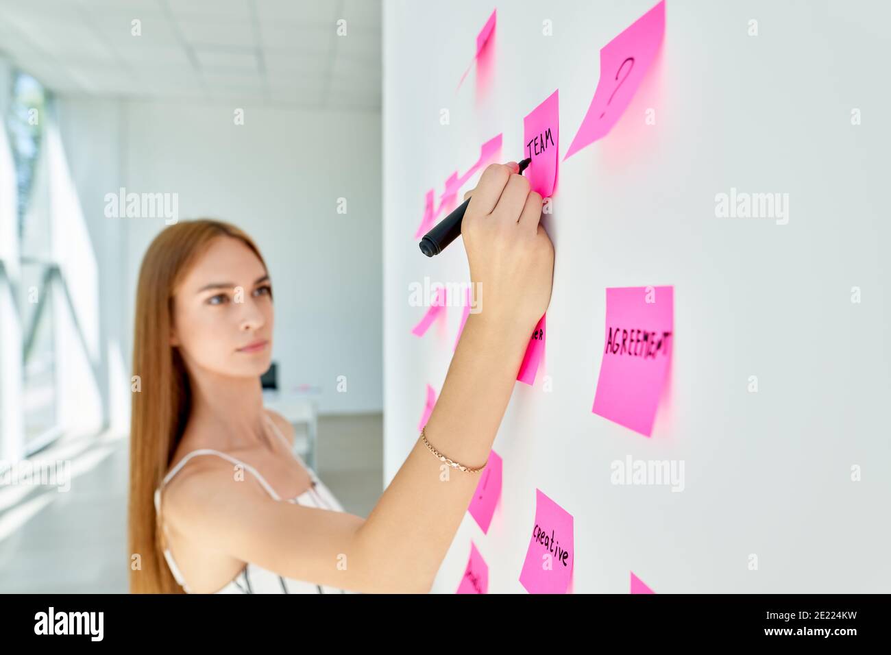 Attractive concentrated business woman using sticky notes to write and ...