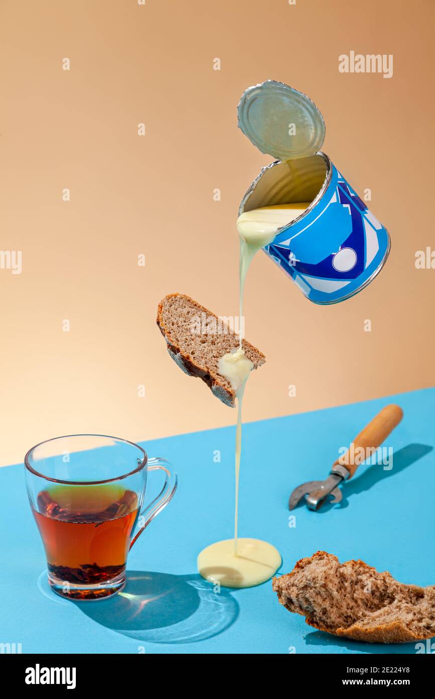 Puddle of condensed milk flows from levitating jar, can opener, black ...