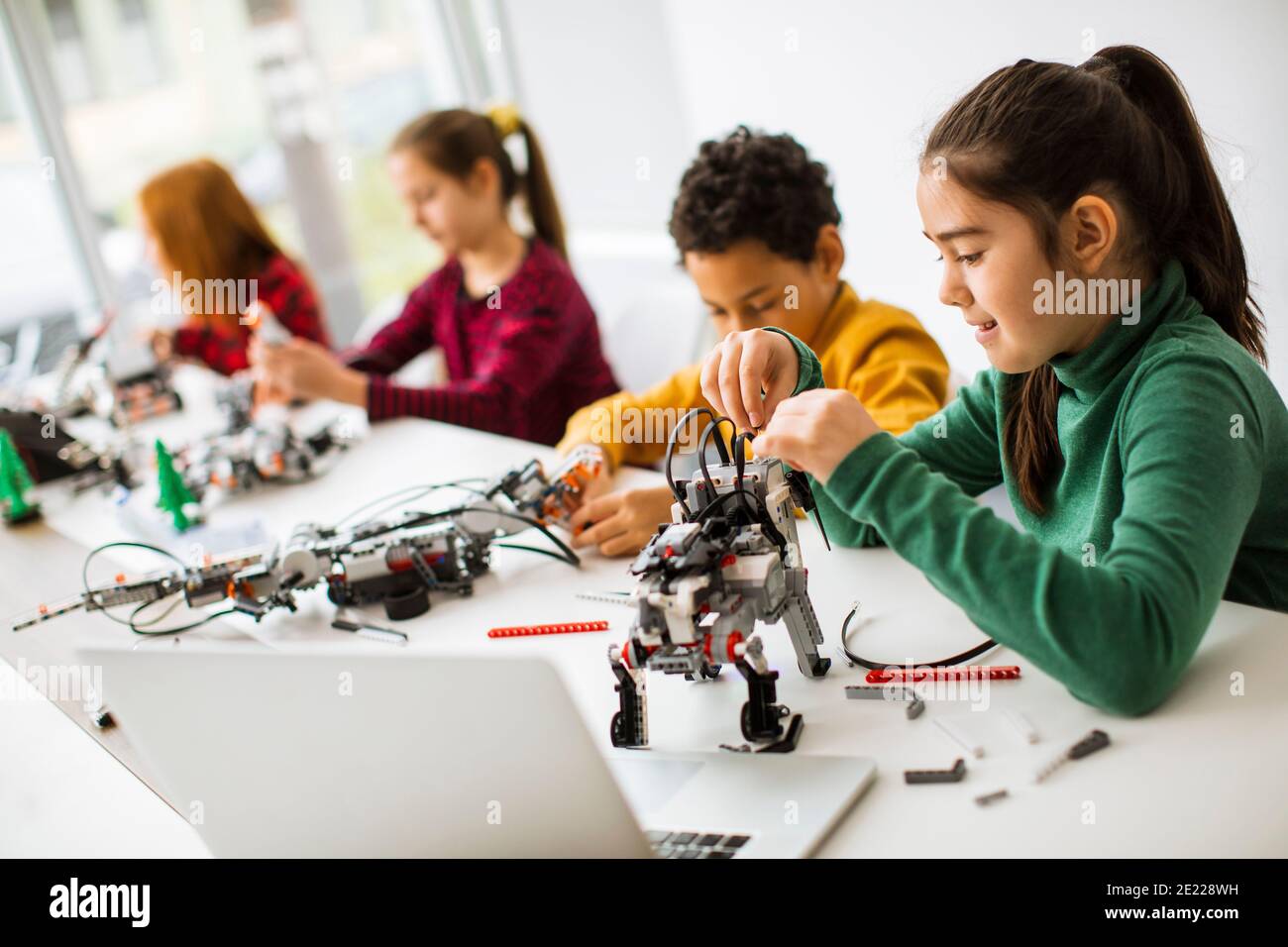 Group of happy kids programming electric toys and robots at robotics ...