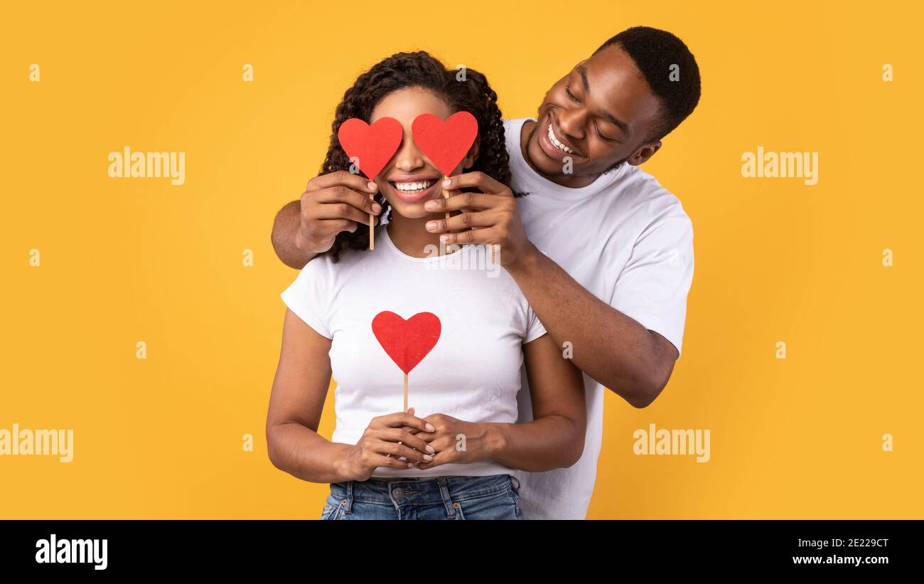 Black Husband Covering Wife's Eyes With Hearts Over Yellow Background ...