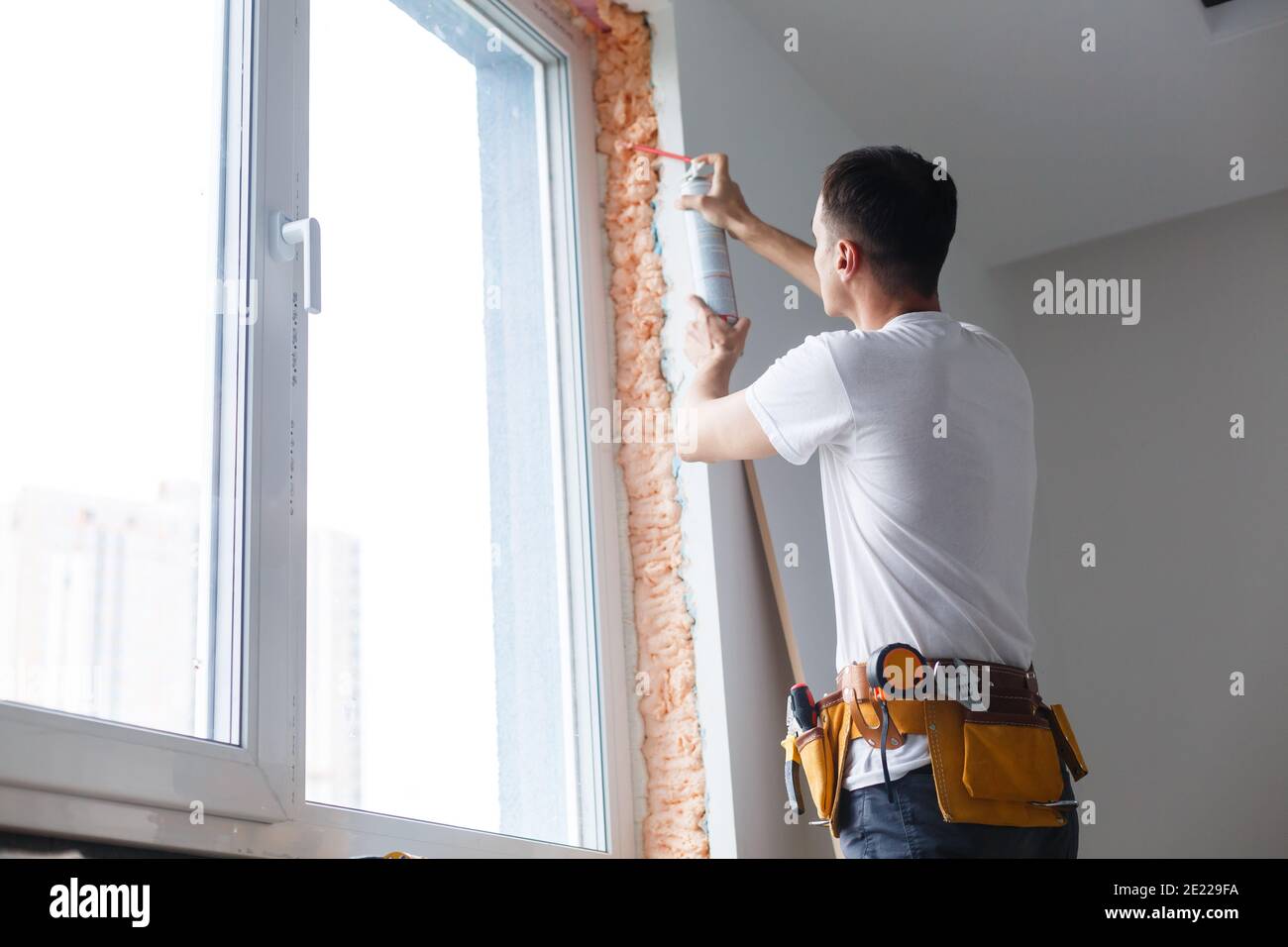 Man putting filling between window and wall in a new house Stock Photo ...