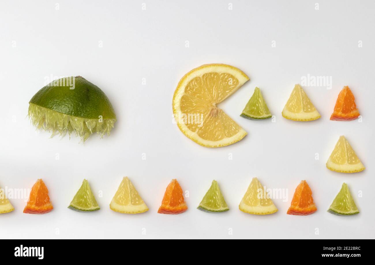 Lemon eats pieces hunted by lime. Pac man minimal citrus fruit flat lay ...