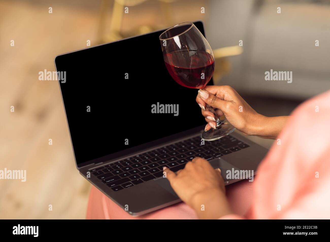 Black woman using laptop with empty mockup screen, drinking wine Stock ...
