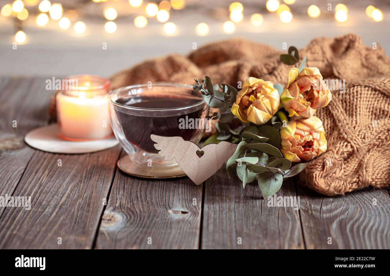 Festive still life with a drink in a cup, flowers and a knitted item on ...