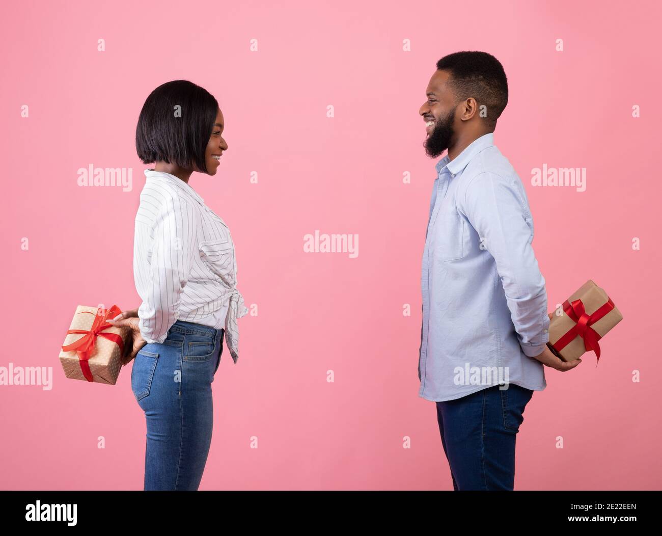 Side view of romantic sweethearts hiding gifts for Valentine's Day or ...