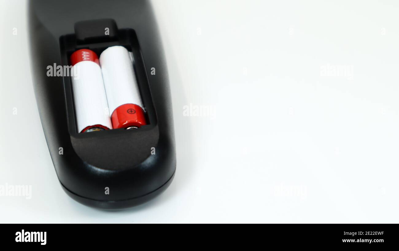Black TV remote control with AAA alkaline batteries in red and white on ...