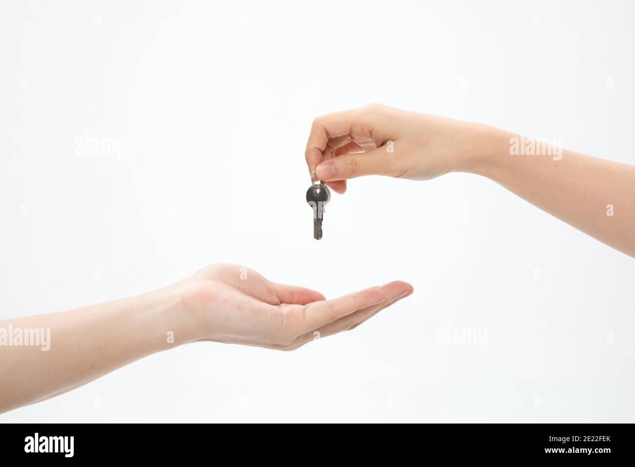 Hand dropping a key into another hand on a white background Stock Photo ...