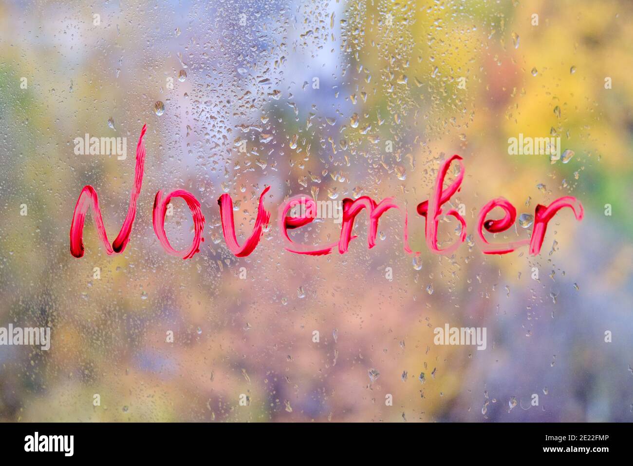 On the window pane is written "November." Glass with water drops on an ...
