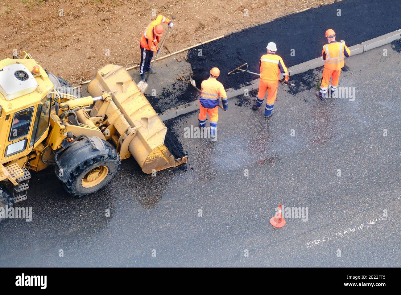 Road works after rain with laying asphalt with shovels from the bucket ...