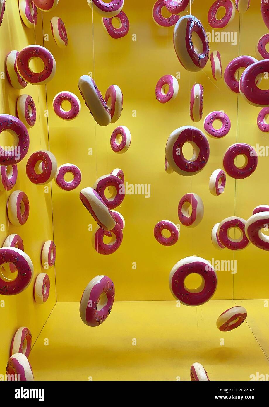 Vertical shot of donut figures hanging from ropes in a yellow room ...