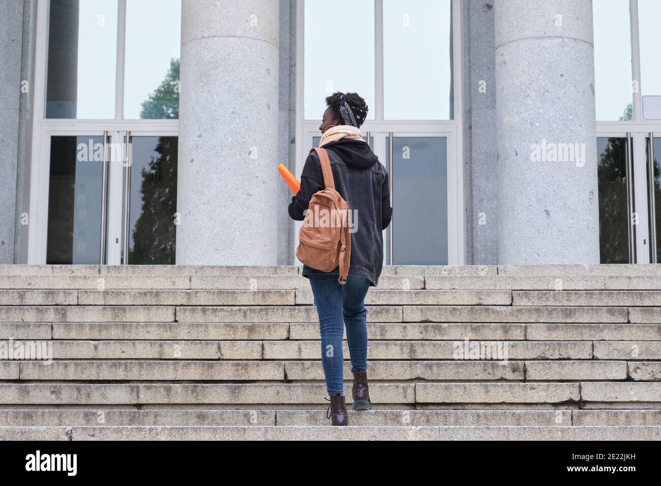 university female african student climbing stairs to enter into the ...