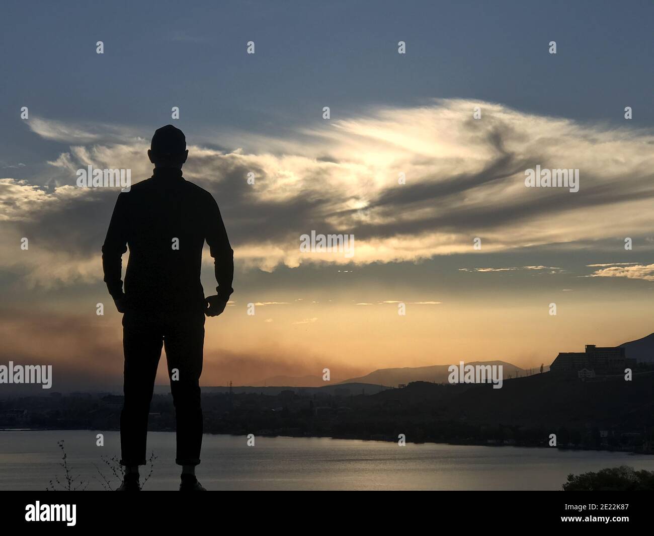 Back view of a silhouette of a young man standing with a majestic ...