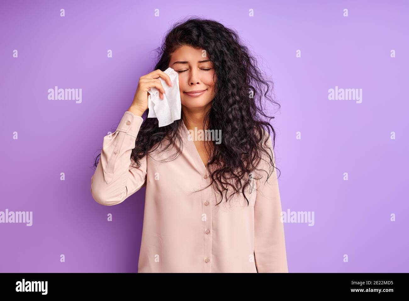 woman stand crying isolated over purple background, use a handkerchief ...