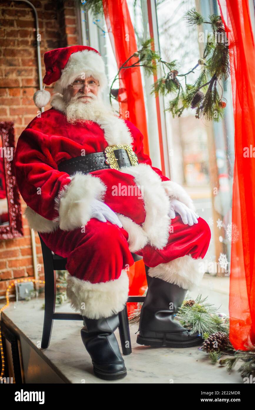 Santa sitting in window display Stock Photo - Alamy