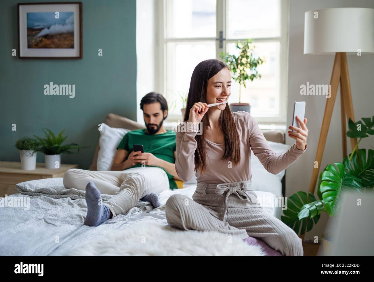 Young couple using smartphones on bed indoors at home Stock Photo - Alamy
