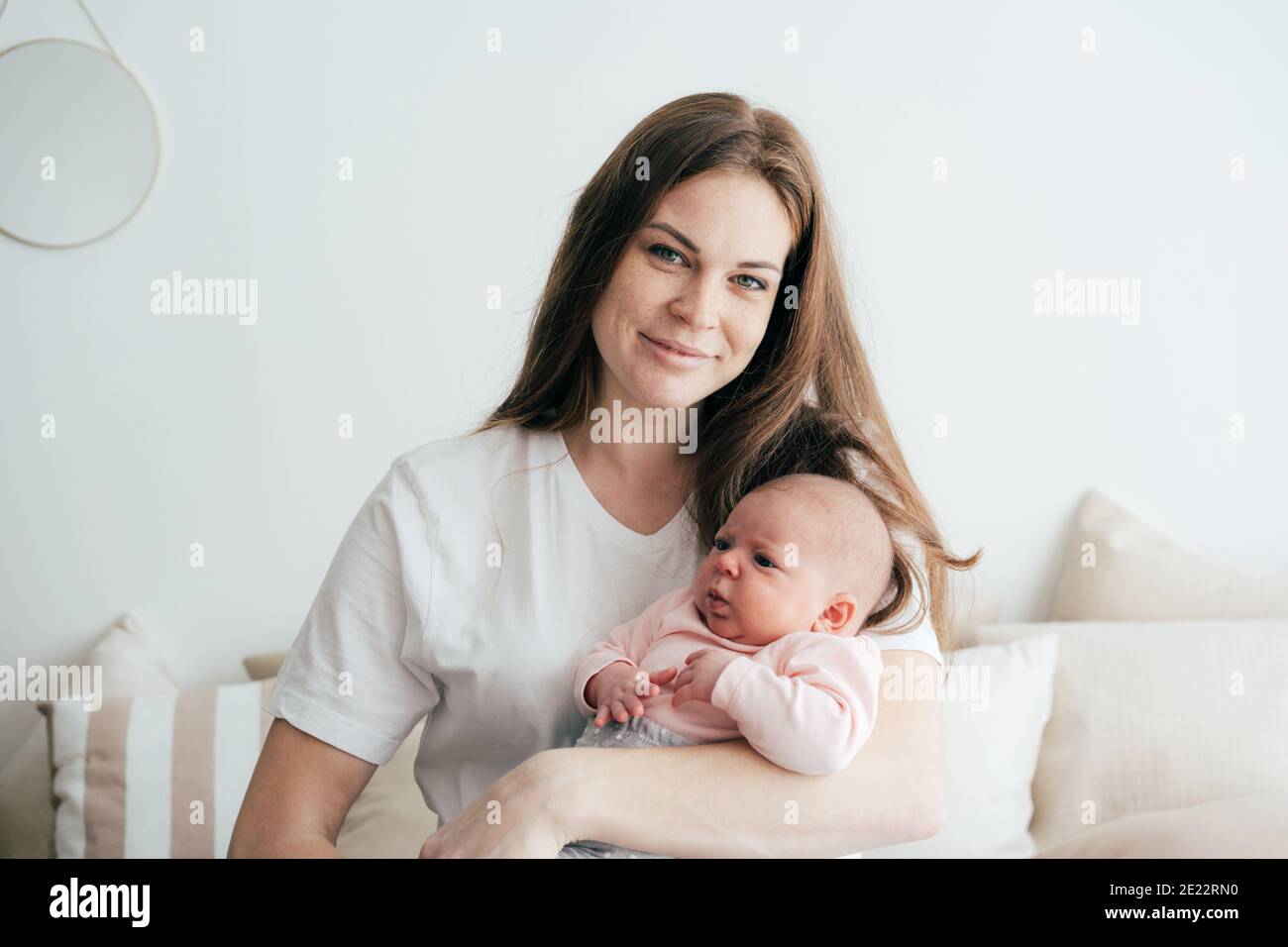 Beautiful young redhead freckled mom holds and hugs a newborn month old ...