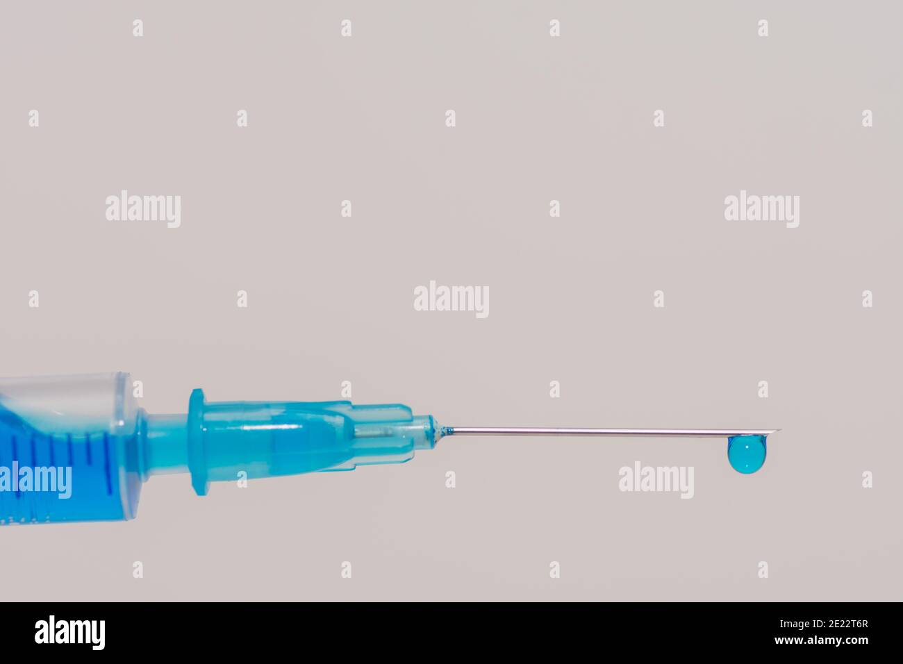 syringe with a blue fluid vaccine and a drop on the front bottom view ...