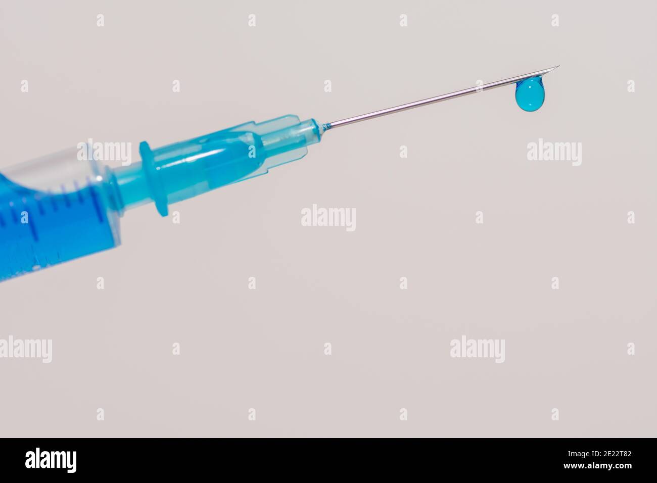 syringe with a blue fluid vaccine and a drop on the front detail view ...