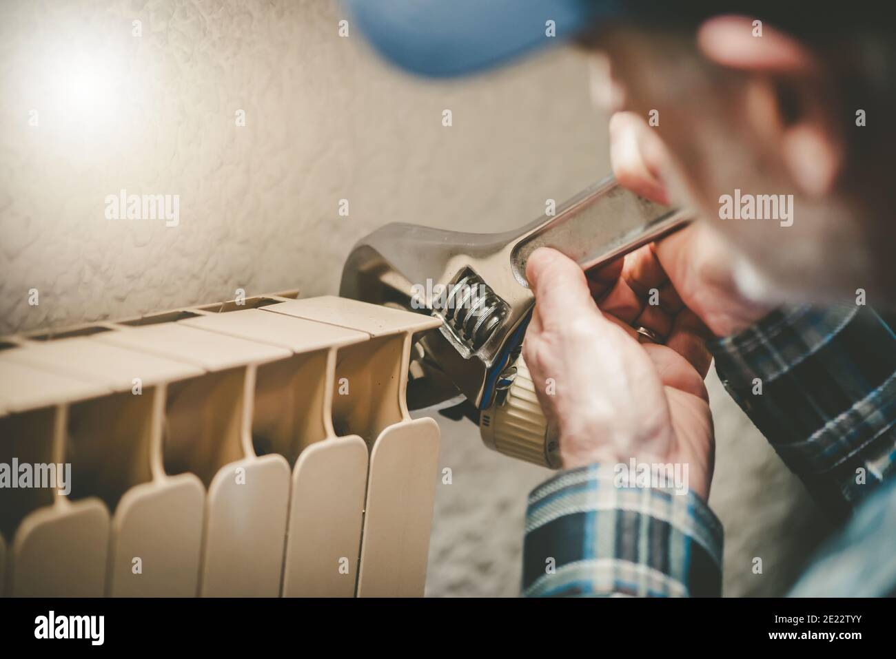 Repairman working on radiator with wrench Stock Photo - Alamy