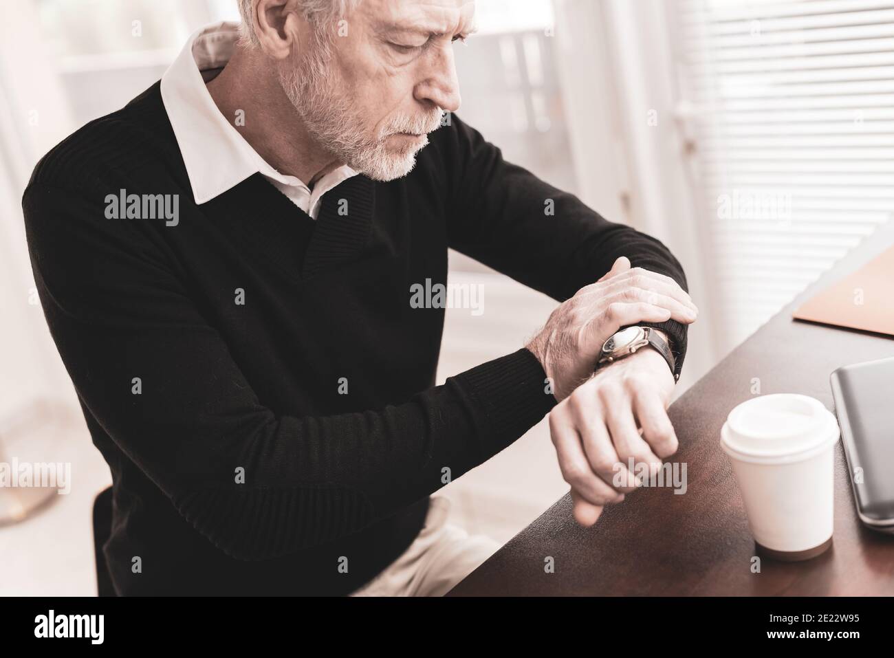 Senior businessman checking time on his wrist watch Stock Photo - Alamy