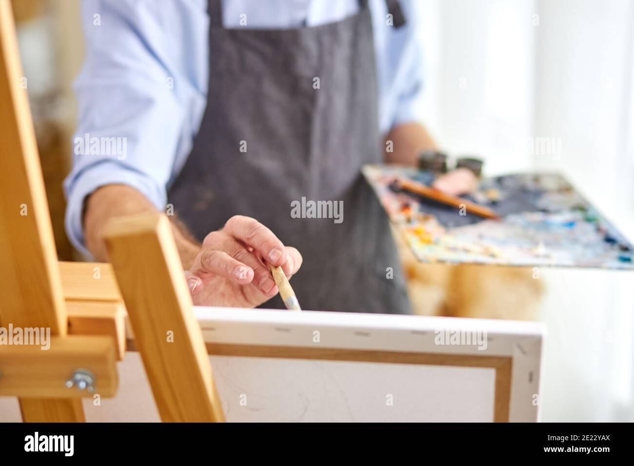 artist applying paint on canvas with paintbrush, his mind full of ...