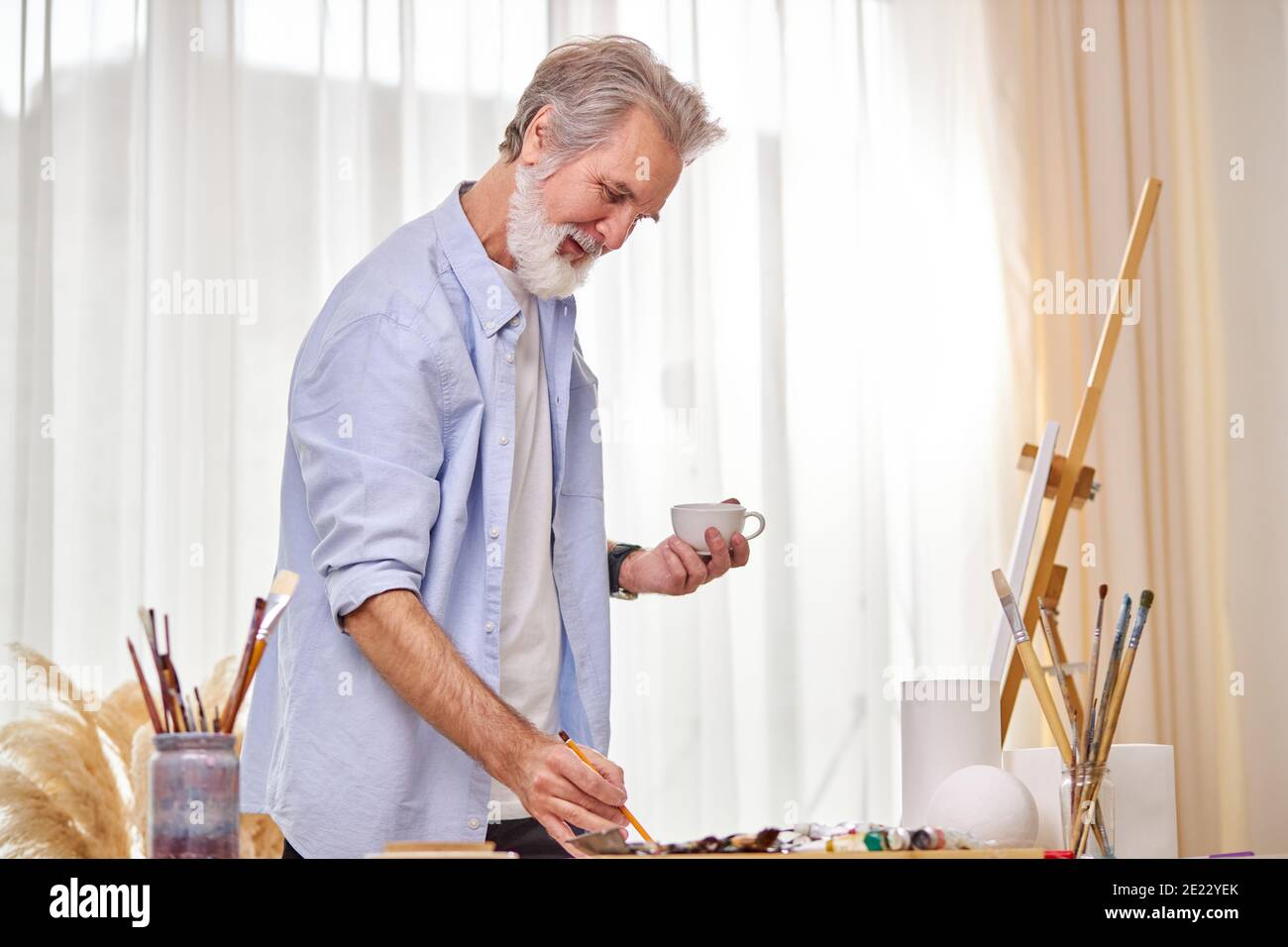 senior artist man draw a sketch on paper and drink tea, enjoy working ...