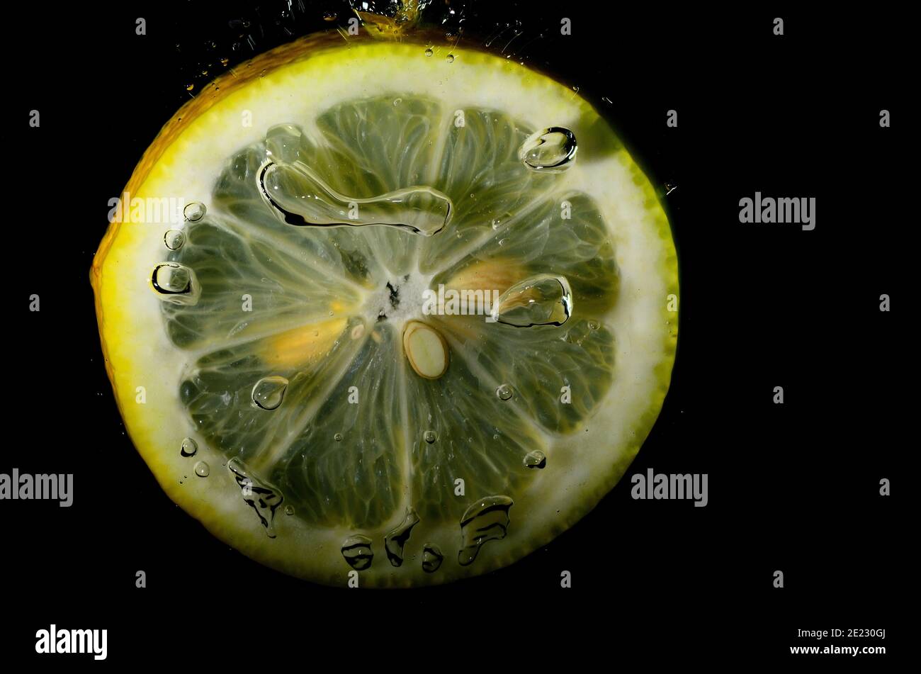 fresh yellow lemon slice in water with bubbles and black background ...