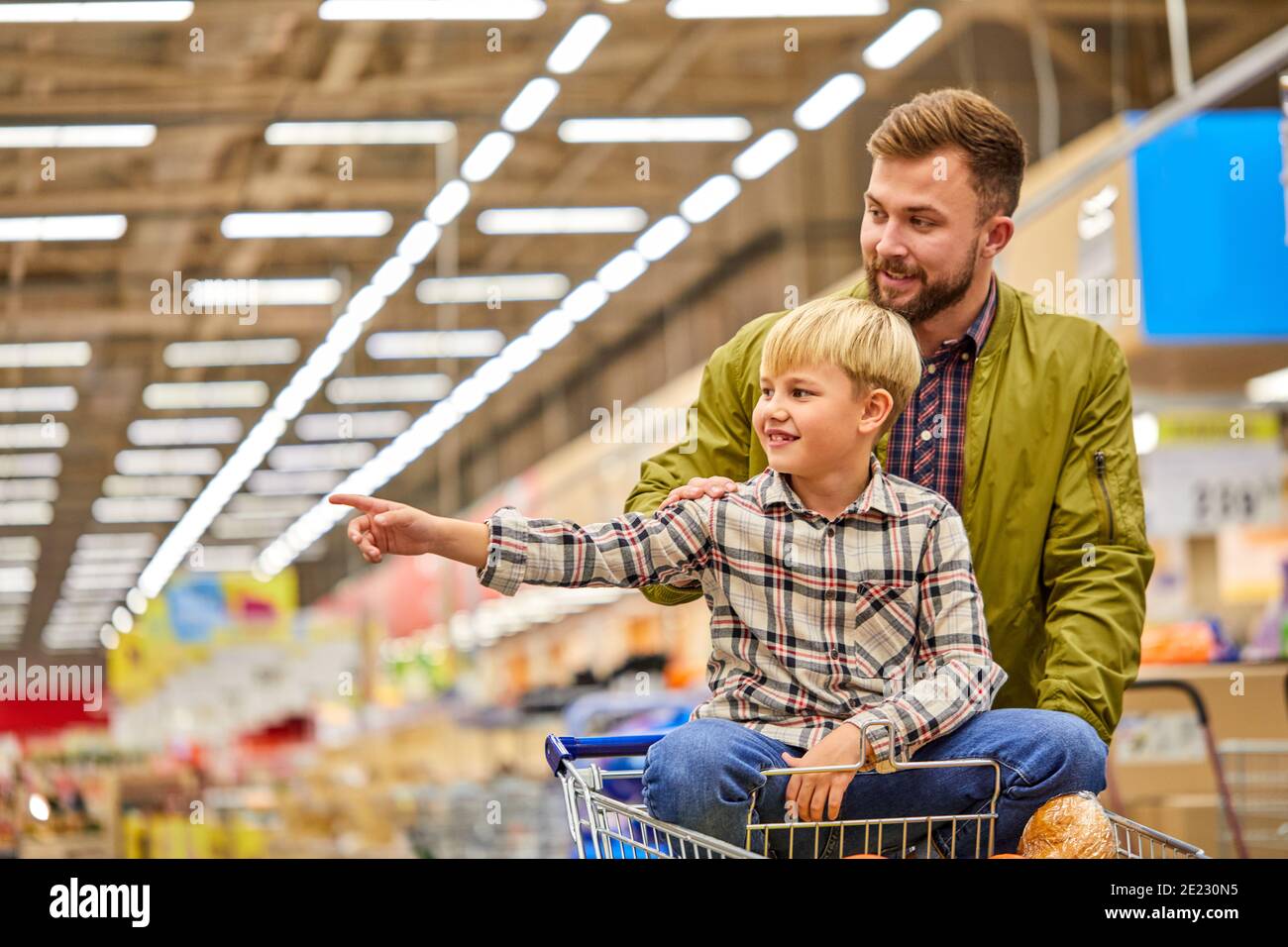 kid boy point finger at side in store during shopping with father ...