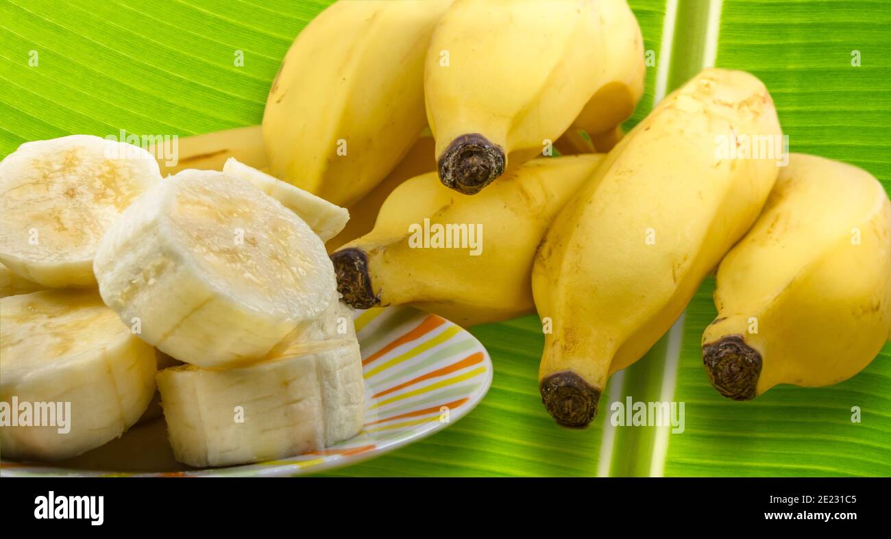 Closeup shot of fresh bananas on a leaf and cut banana pieces on a ...