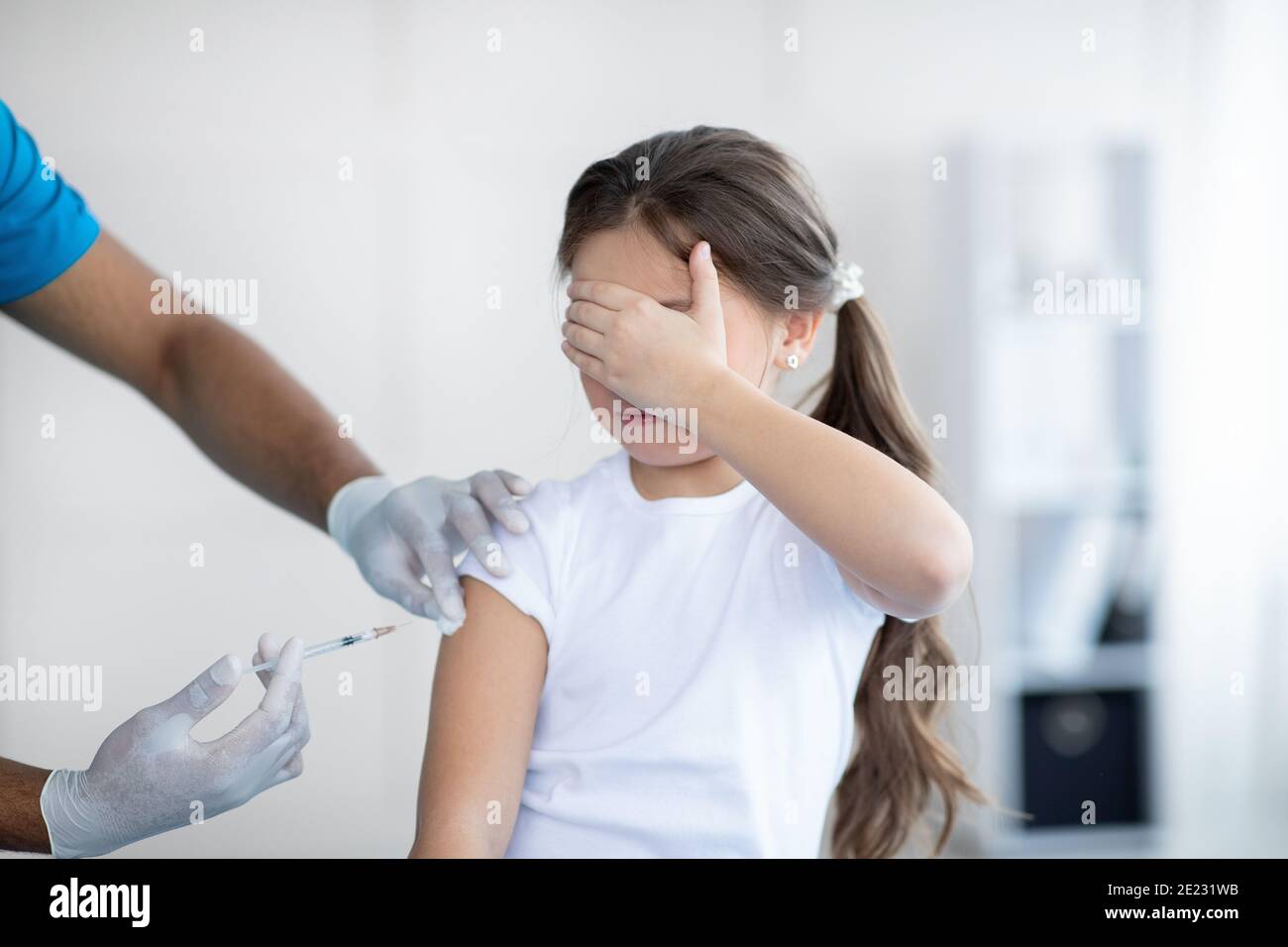 Scared little girl receiving covid-19 vaccine, covering her eyes in ...