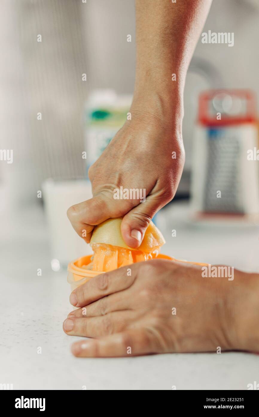 Squeeze lemon by hand with lemon juicer in kitchen Stock Photo - Alamy
