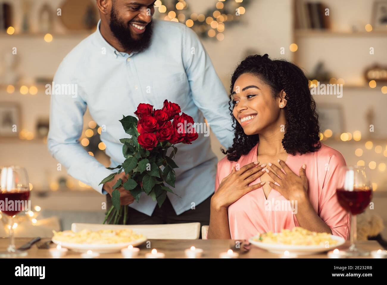 Young black man giving red roses to woman Stock Photo - Alamy