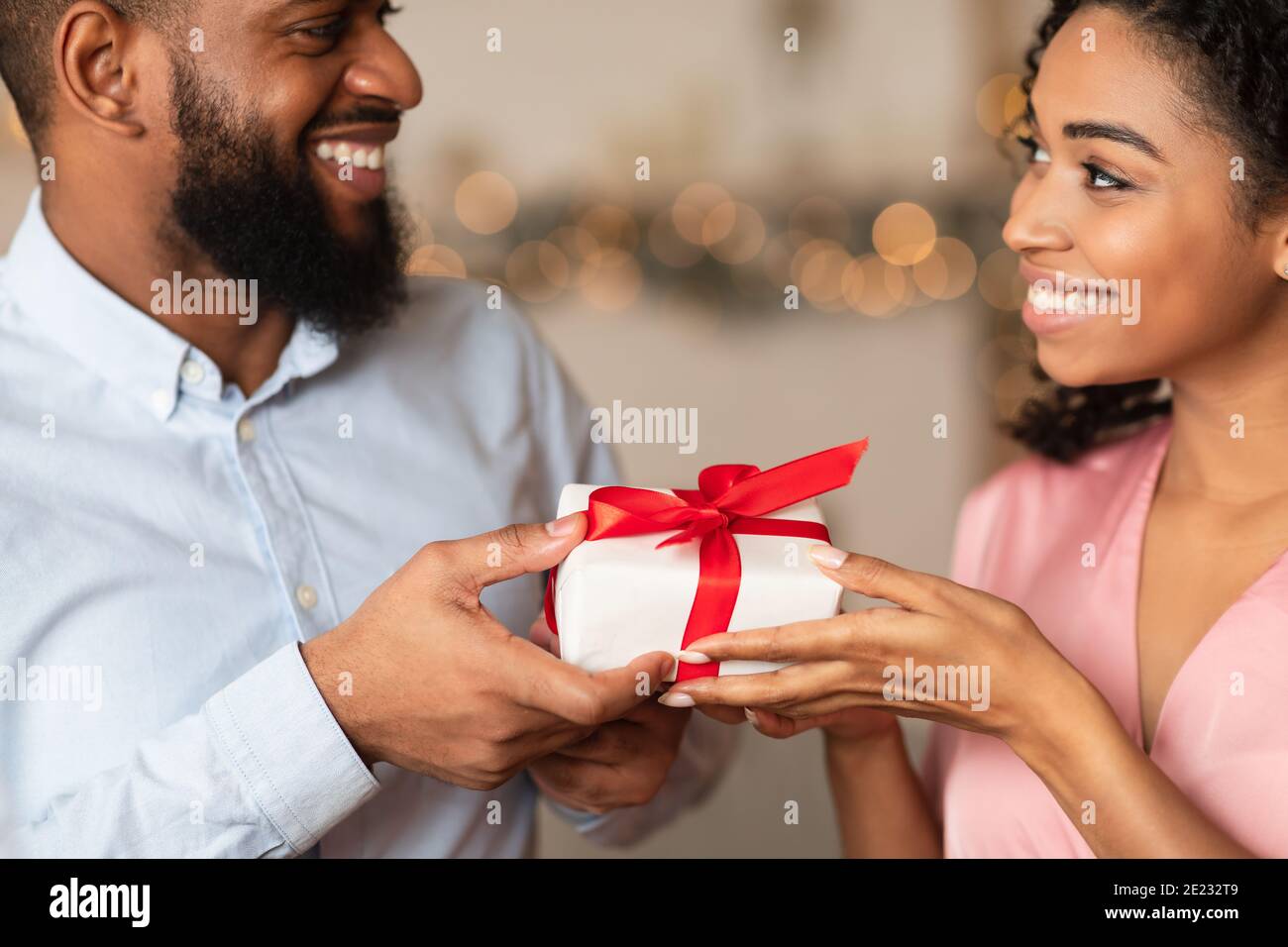 Young black man giving gift box to his happy woman Stock Photo - Alamy