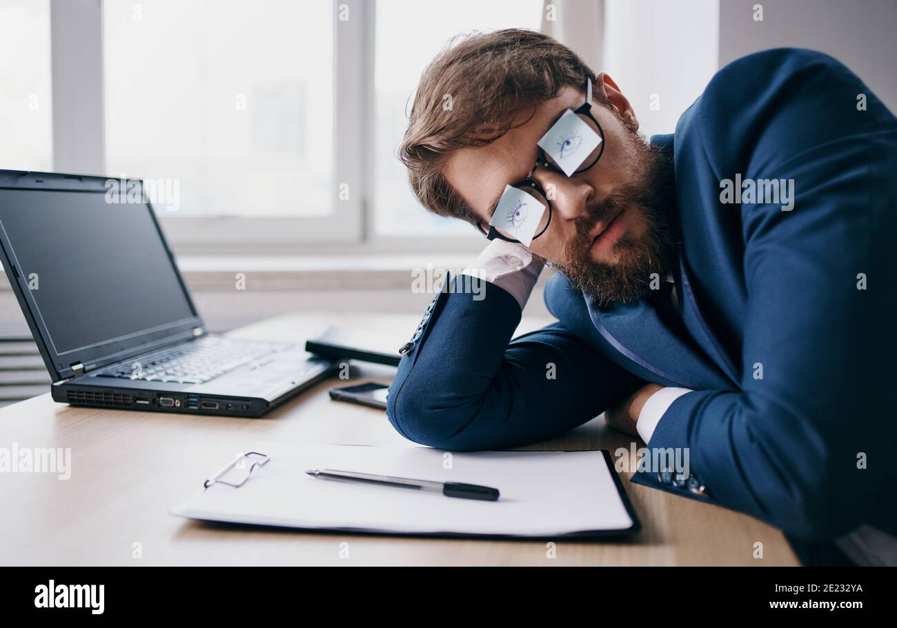 Business man sleeping at work wearing glasses with sheets of paper ...