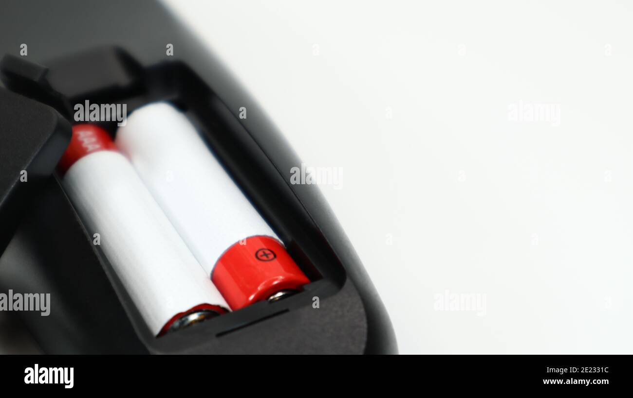 Black TV remote control with AAA alkaline batteries in red and white on ...