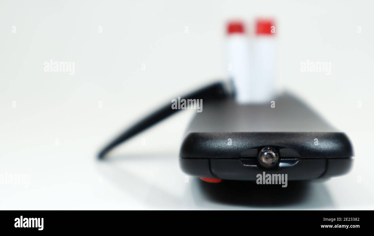 Black TV remote control with AAA alkaline batteries on a white ...
