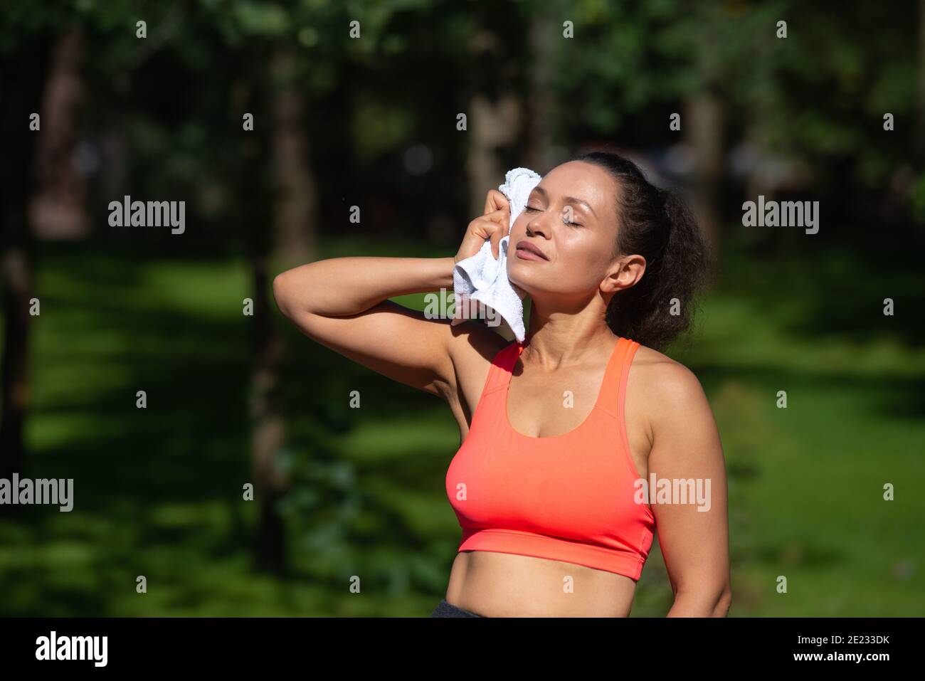 Happy sporty woman wipe her face with towel after productive exercising ...