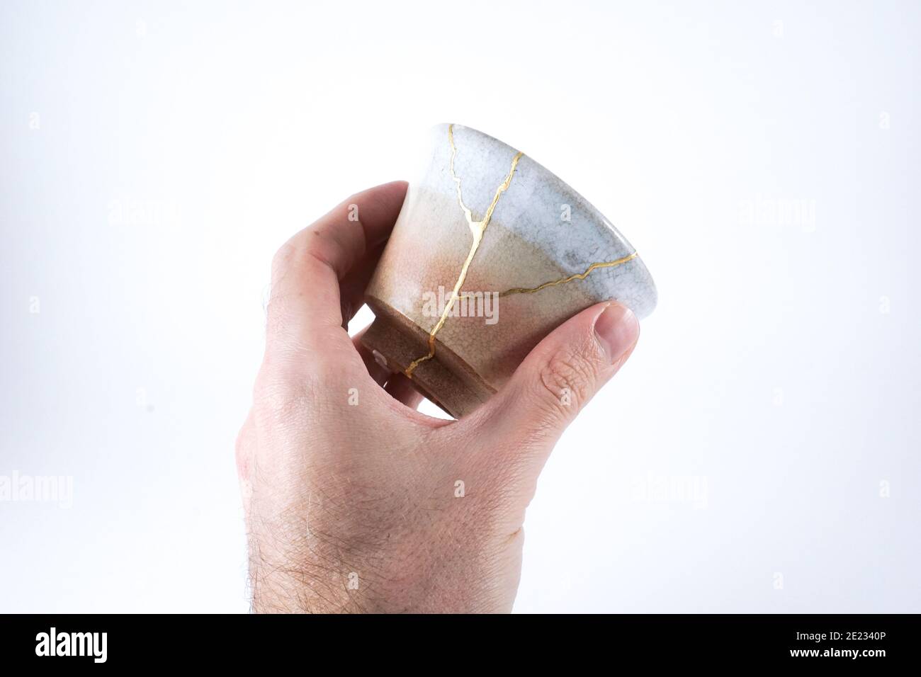 Japanese Kintsugi beige tea cup, gold cracks on antique pottery Stock ...