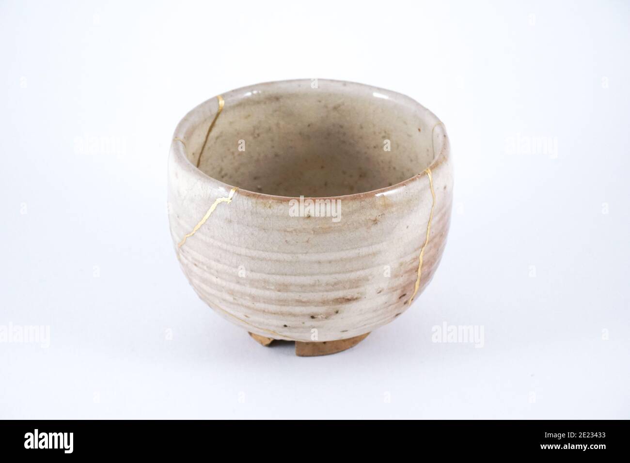 Japanese Kintsugi beige tea cup, gold cracks on antique pottery Stock ...