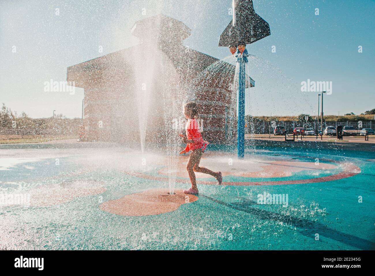 Cute adorable Caucasian funny girl playing on splash pad playground on ...