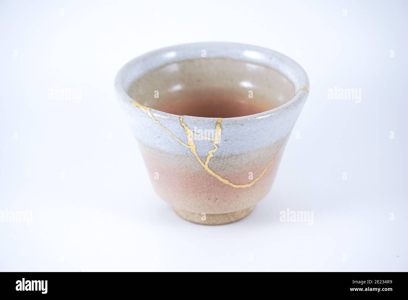Japanese Kintsugi beige tea cup, gold cracks on antique pottery Stock ...