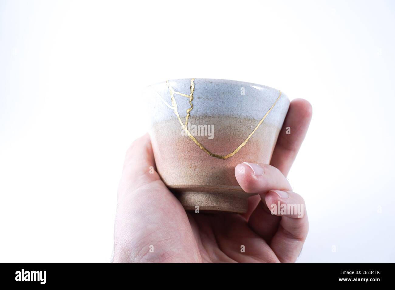 Japanese Kintsugi beige tea cup, gold cracks on antique pottery Stock ...