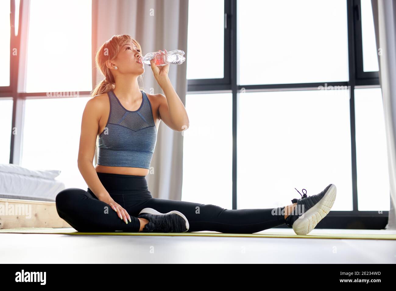 asian woman takes a sip of fresh water after exercise, workout. female ...