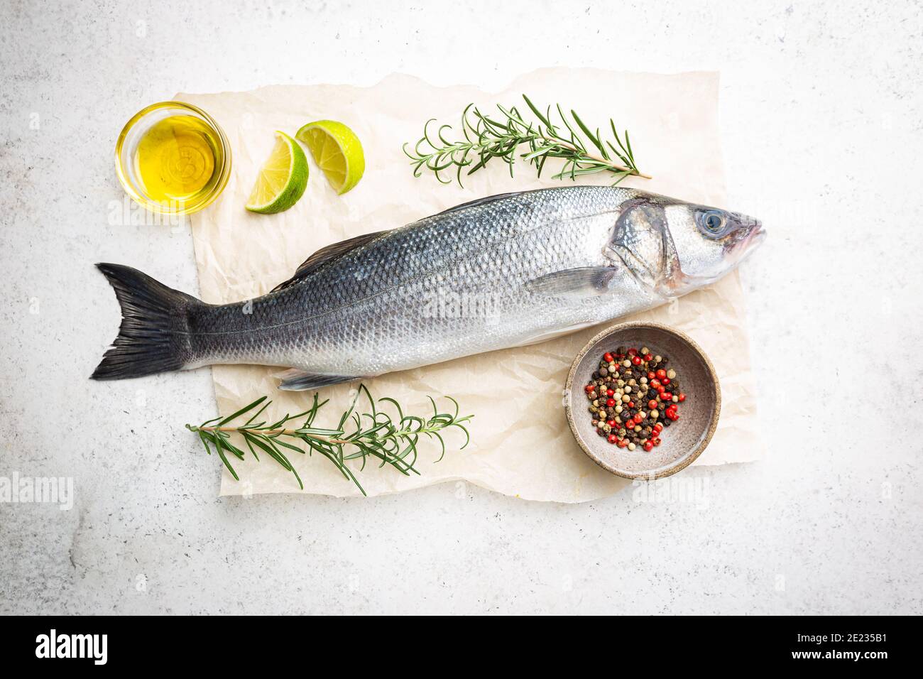 Raw seabass fish with rosemary and spices on white background, top view ...