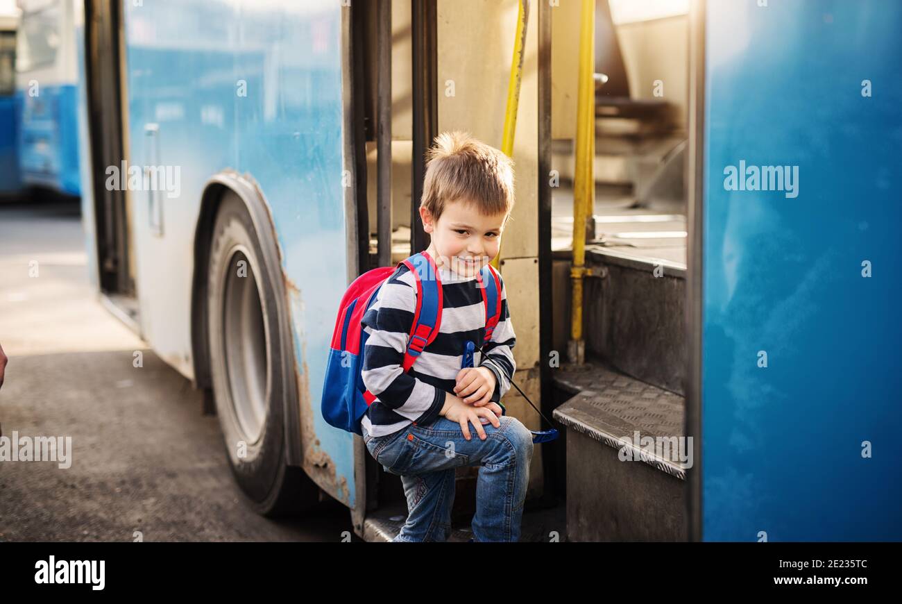 Cute small boy is entering a bus with a school bag on his back Stock ...