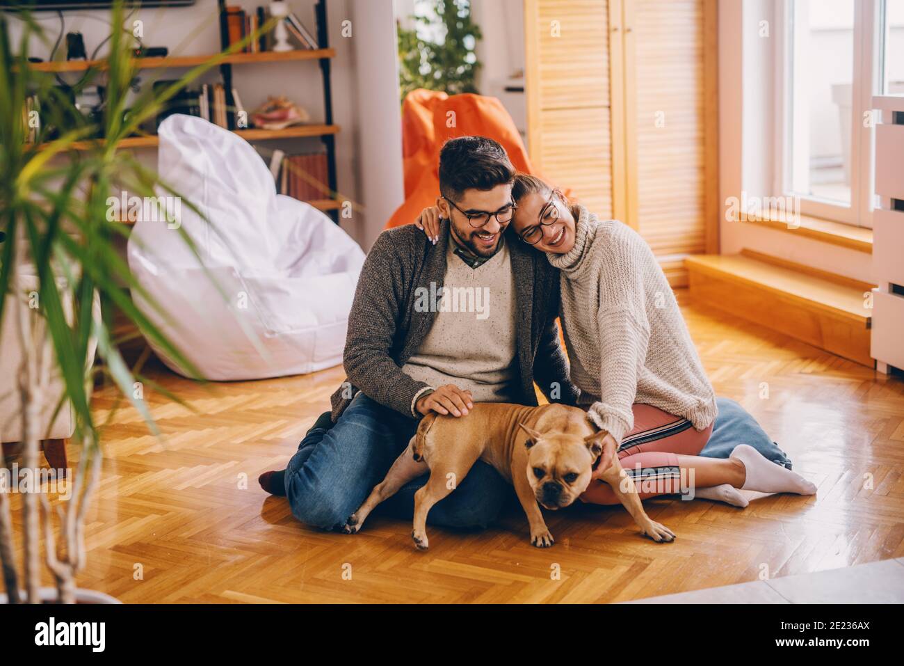 Adorable happy couple hugging and holding their dog. Home interior ...